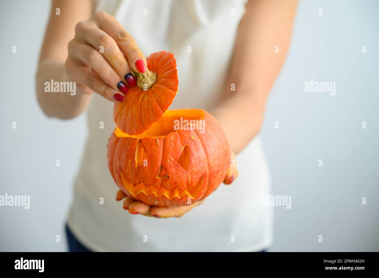 Female hands holding a pumpkin for Halloween. Close-up of a woman opens ...
