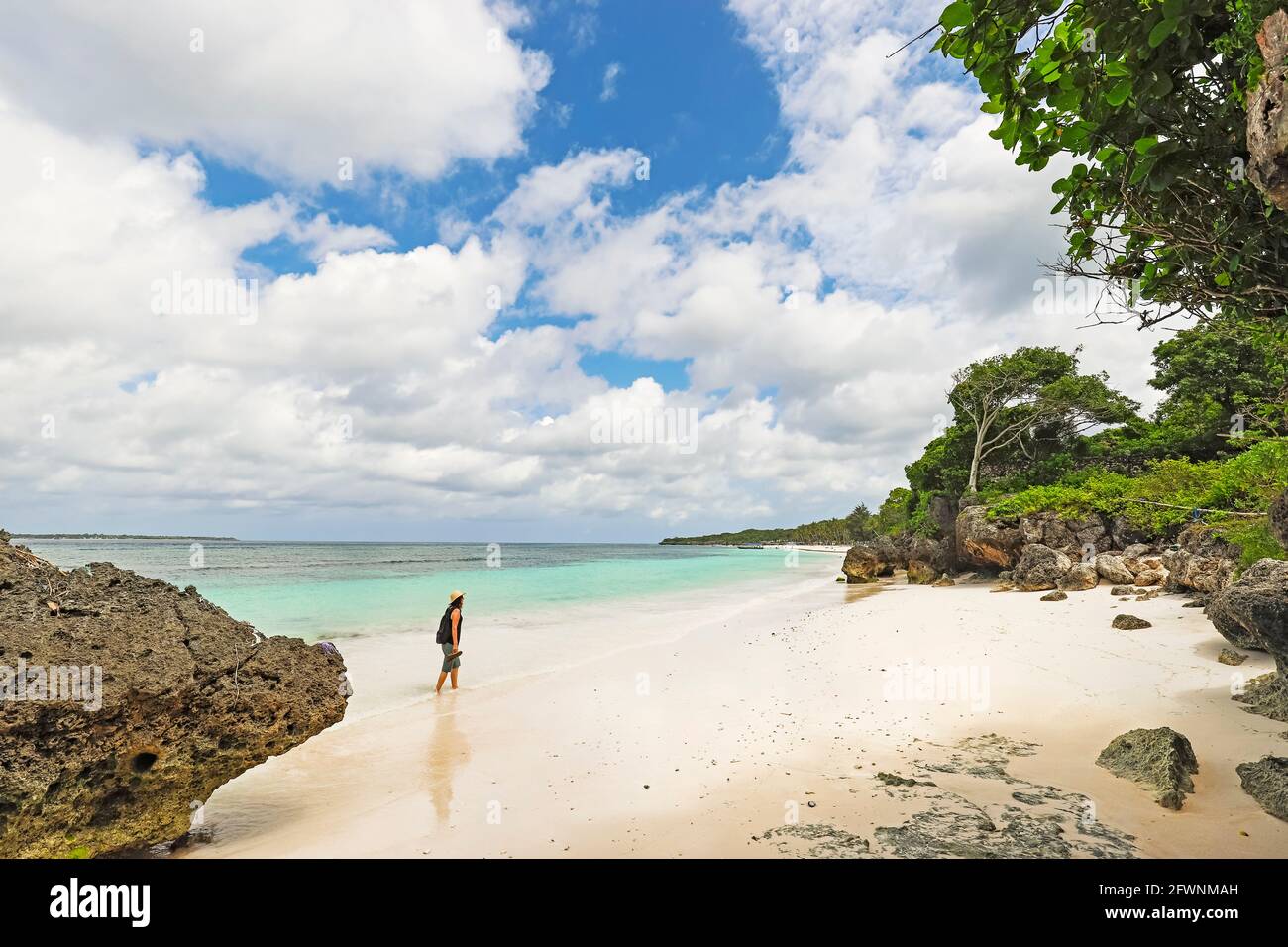 Tourist exploring eroded limestone rock bay & fine white sand beach at ...