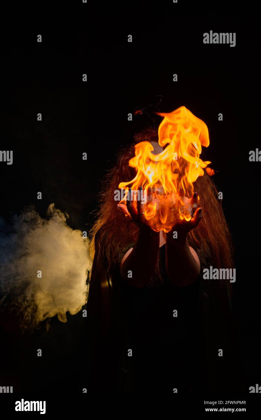 An evil red-haired witch holds fire in her hands Stock Photo - Alamy
