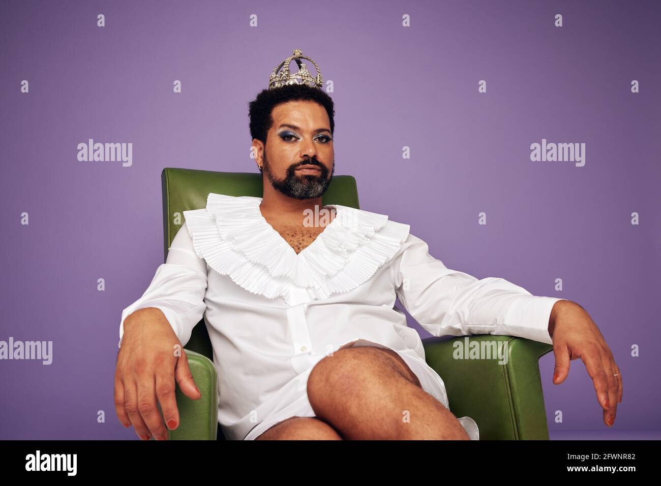 Confident drag queen sitting on arm chair. Man with beard wearing ...