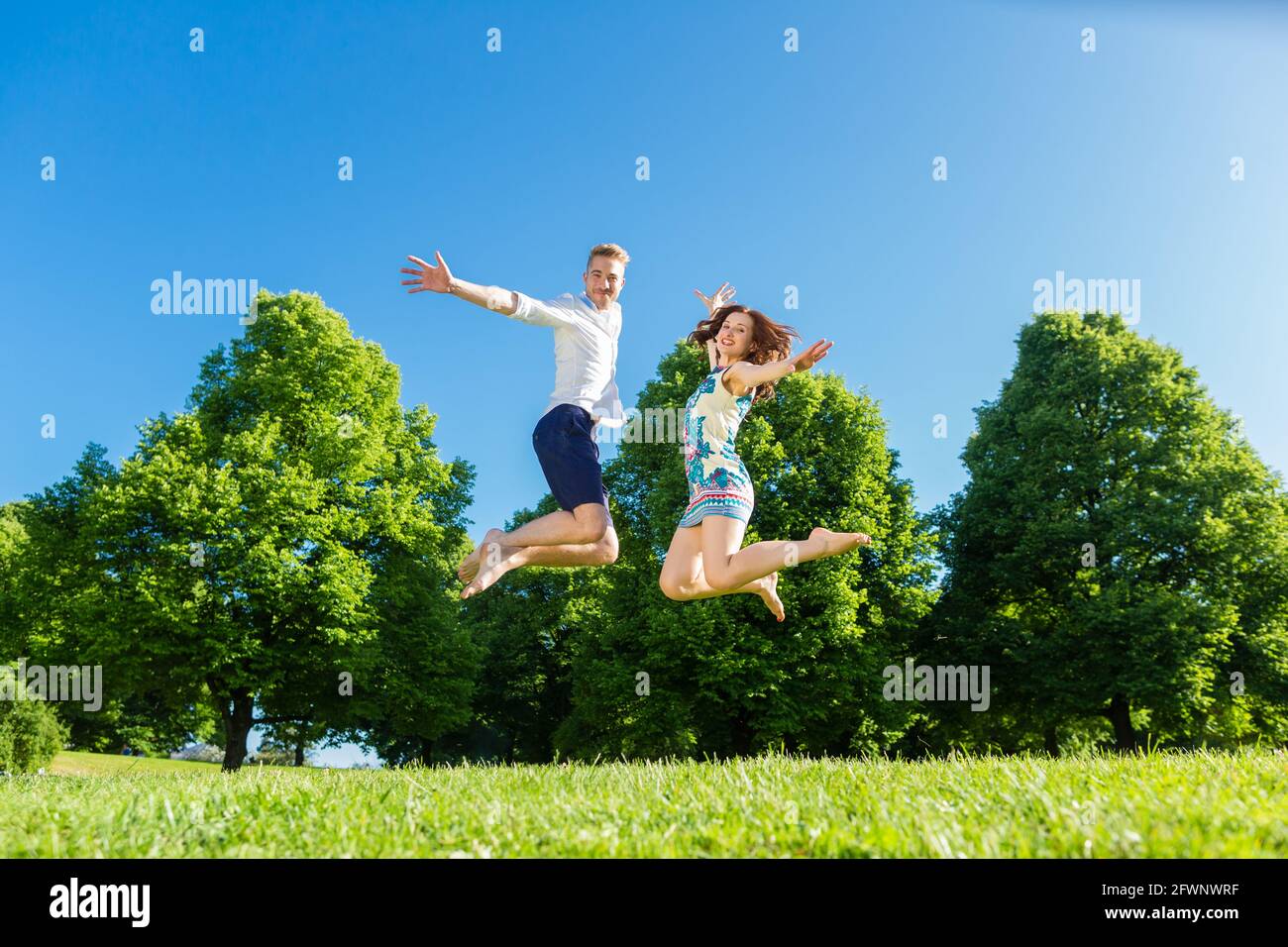 Couple in love jumping on park lawn Stock Photo - Alamy