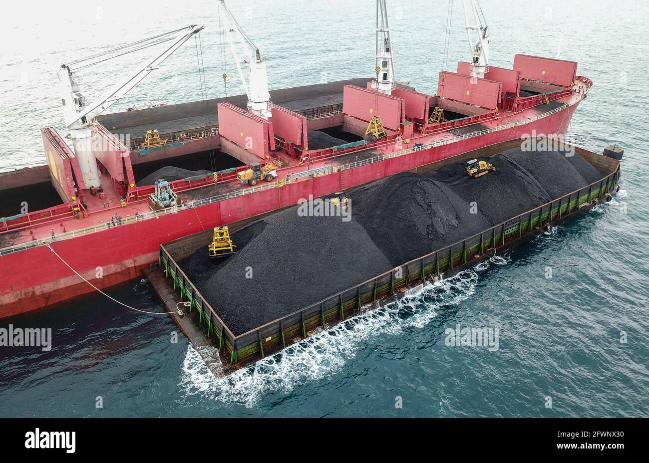 Transporting coal from the barge to the mother vessel aerial view Stock ...
