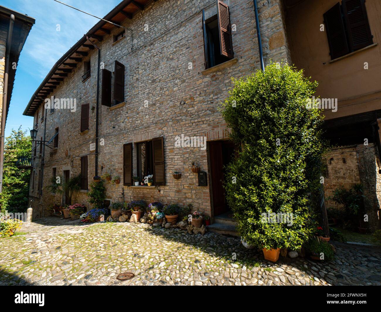 Alleyway with old brick buildings decorated by plants Stock Photo - Alamy