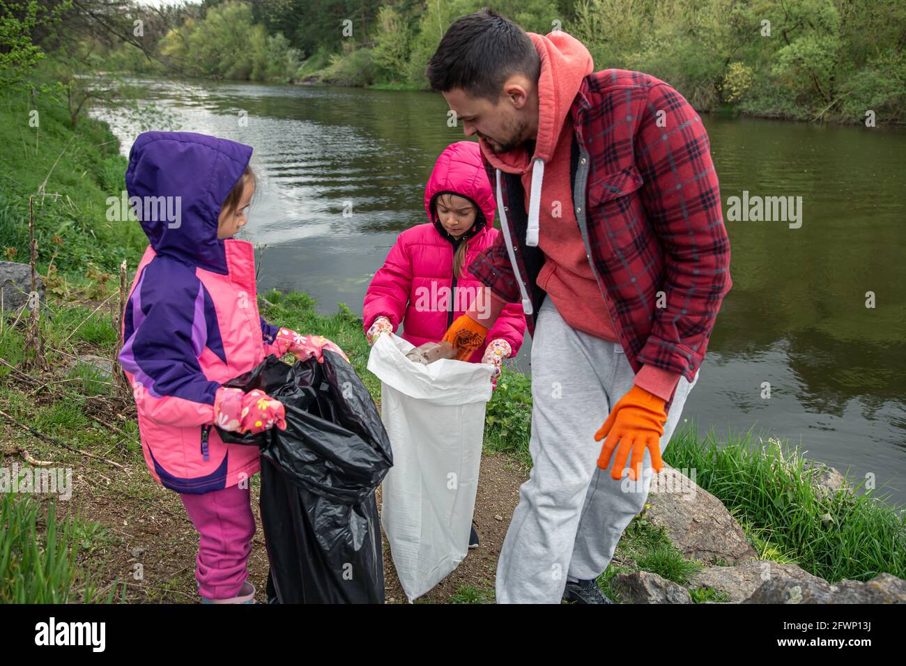 Children and dad are cleaning up garbage in the forest near the river ...