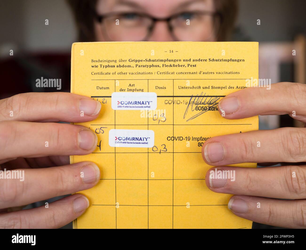 A caucasian woman is holding her International Immunization Certificate ...