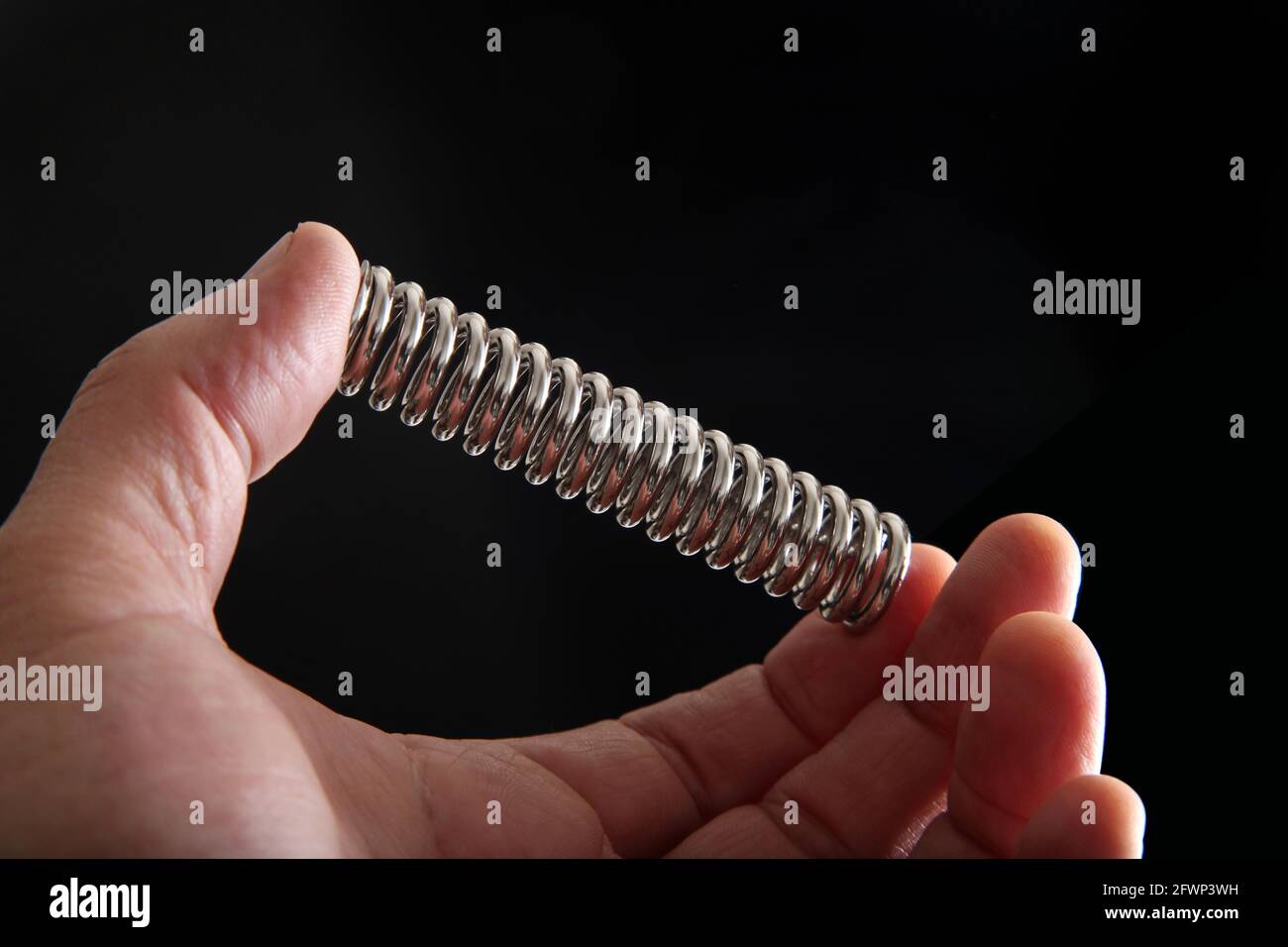 Hand squeezes a metal spring hi-res stock photography and images - Alamy