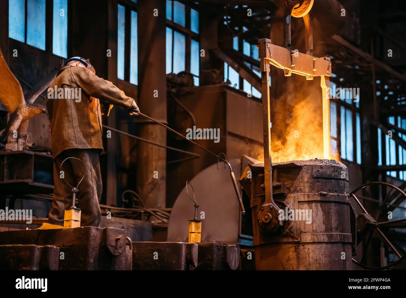 iron cast process, ladle with liquid molten metal and worker ...