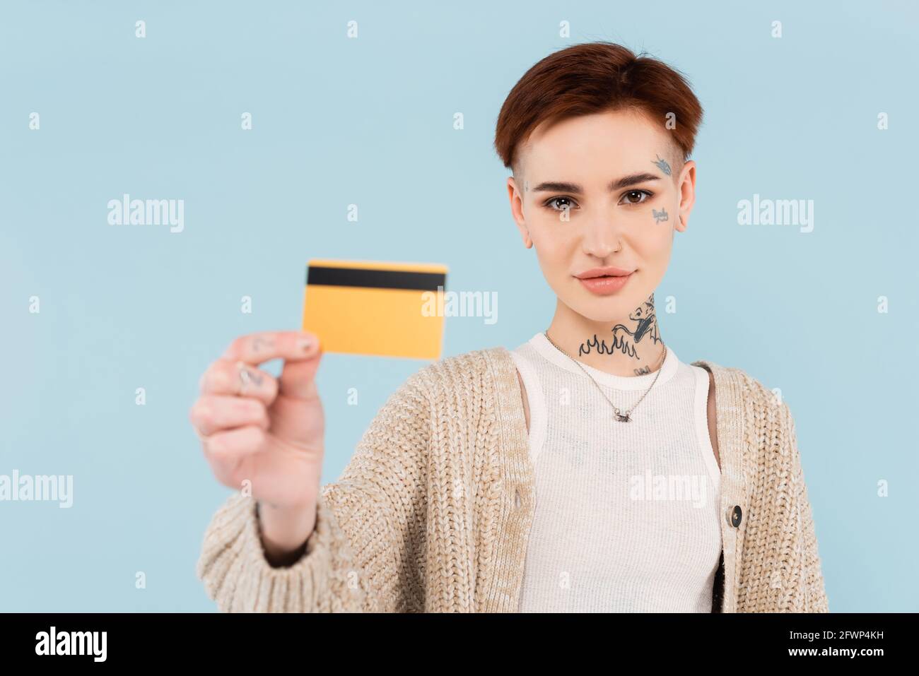 young tattooed woman holding blurred credit card isolated on blue Stock ...