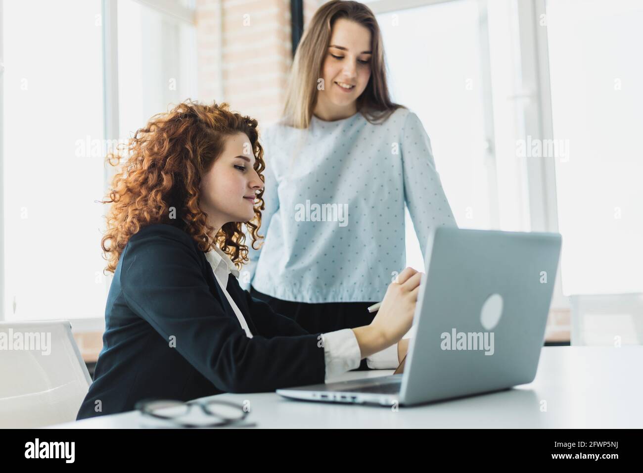 Two beautiful young woman talking and discussing working moments with ...