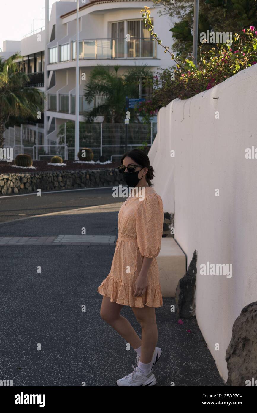 girl in yellow dress walking down the street with black mask Stock ...