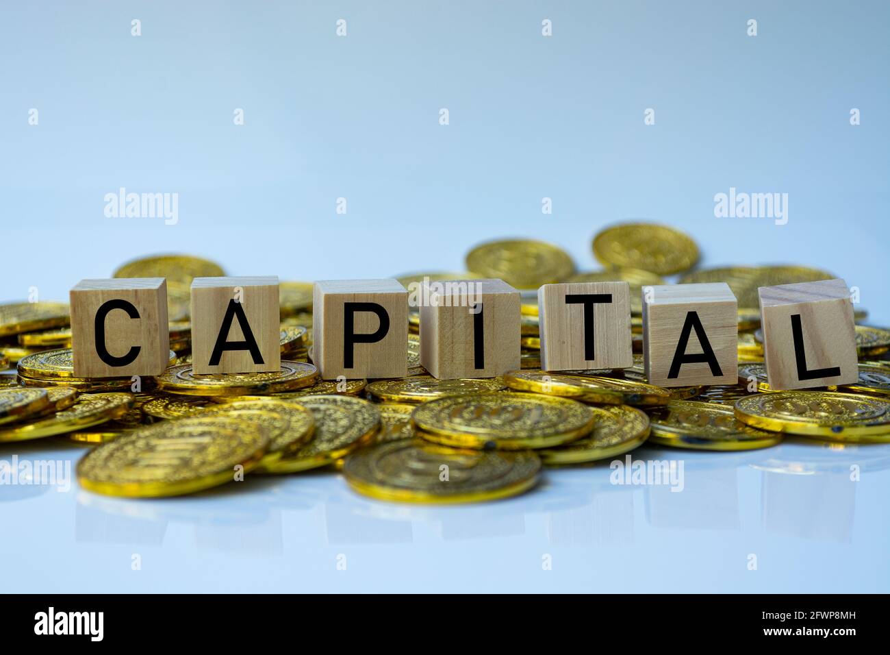 Capital text on wood block with a pile of coins Stock Photo - Alamy