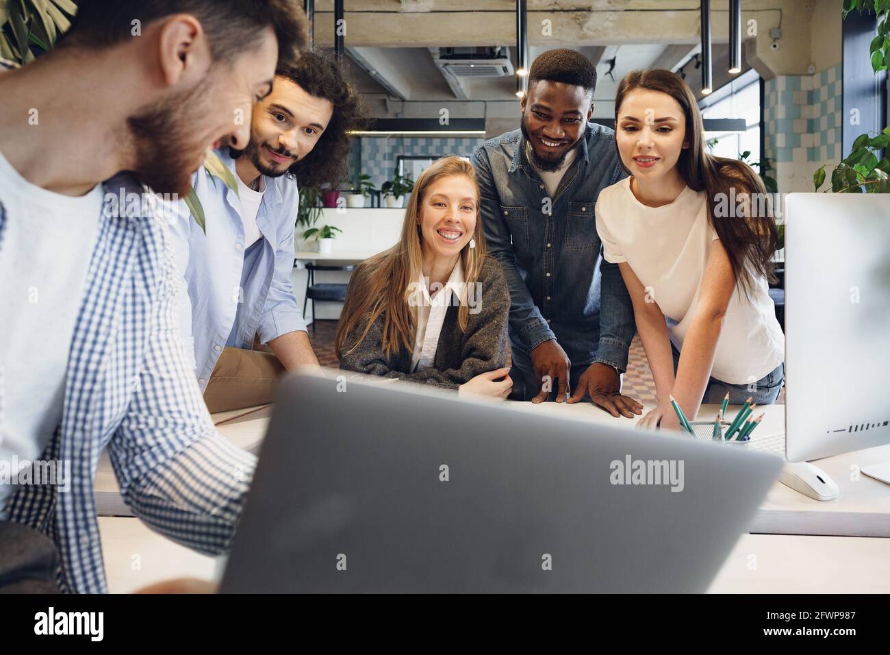 Team of diverse coworkers in modern office discuss their project ...