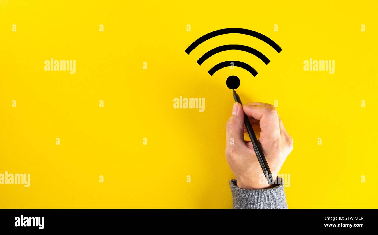 Male hand drawing a wifi signal on yellow color background with copy ...
