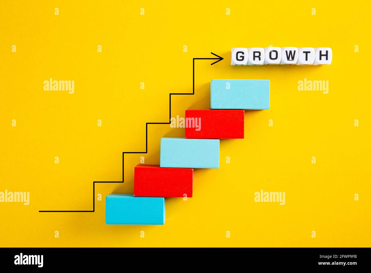 An upward pointing arrow on top of growing graph made of wooden blocks ...