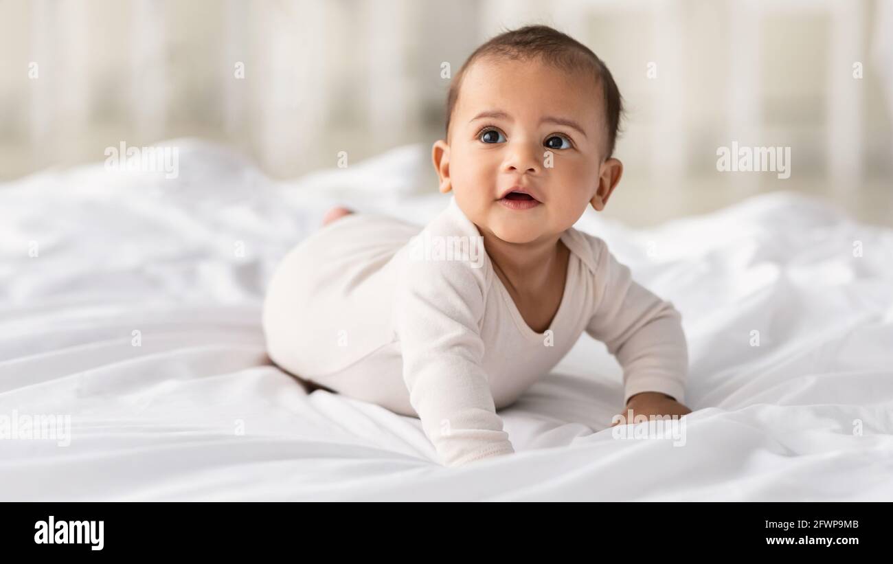 Cute little African American baby crawling on bed at home Stock Photo ...