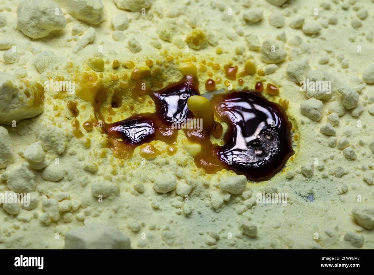 Powdered and molten sulphur, a chemical element. Yellow background ...