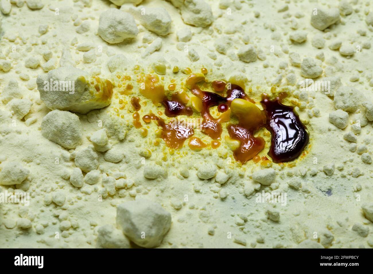 Powdered and molten sulphur, a chemical element. Yellow background ...
