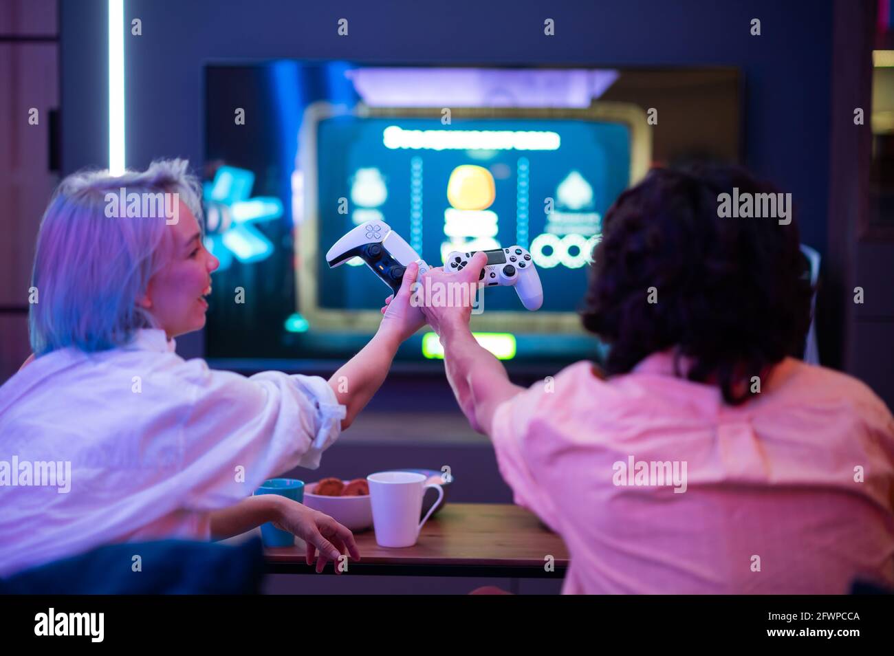 Couple at home playing PlayStation 5 with different generations of ...