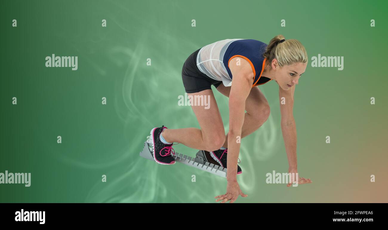 Composition of fit female athlete runner in starting blocks on green ...