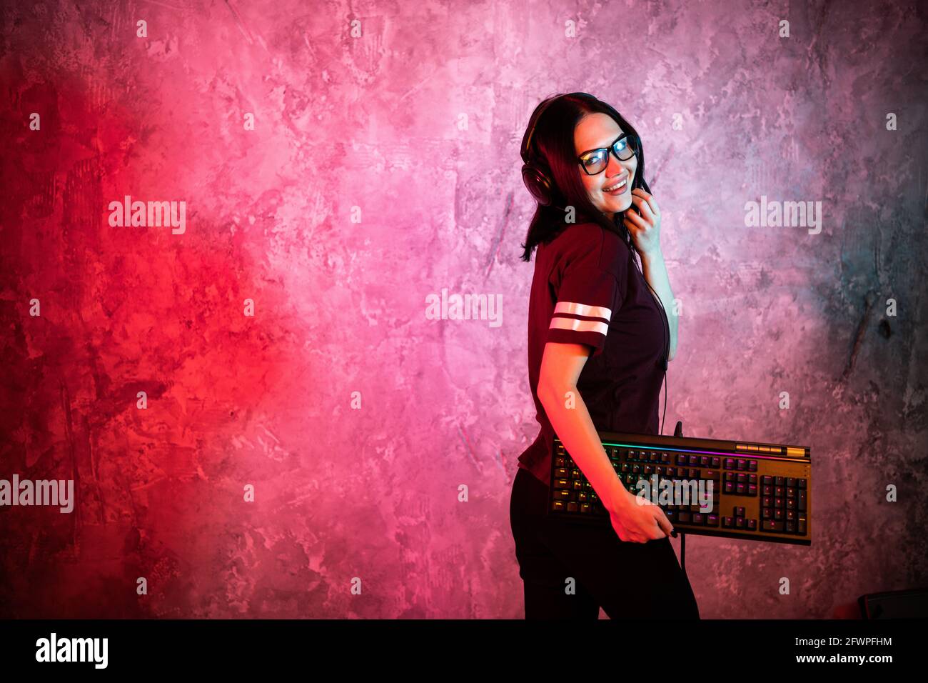 Female esports gamer posing with a gaming gear in neon light. Streamer ...