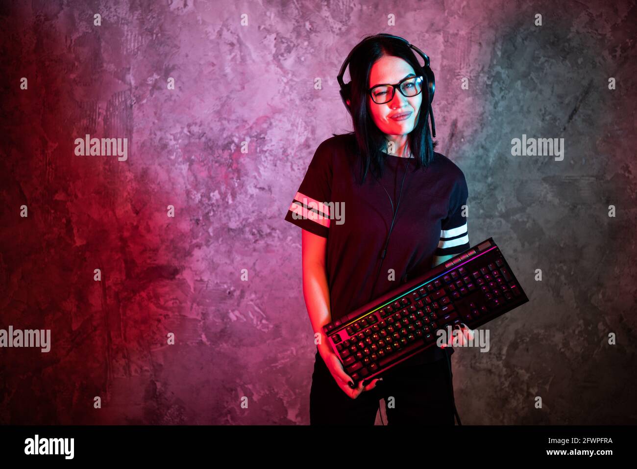 Female esports gamer posing with a gaming gear in neon light. Streamer ...