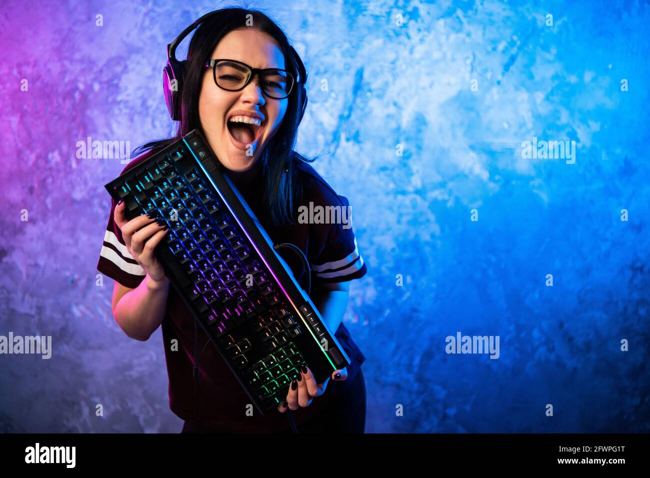 Female esports gamer posing with a gaming gear in neon light. Streamer ...