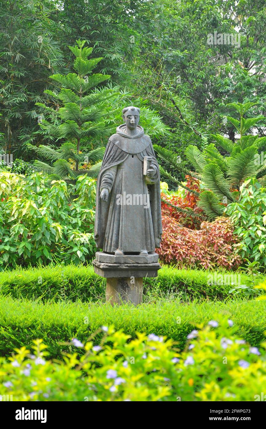 Old statue in a garden surrounded by flowers and green plants Stock ...