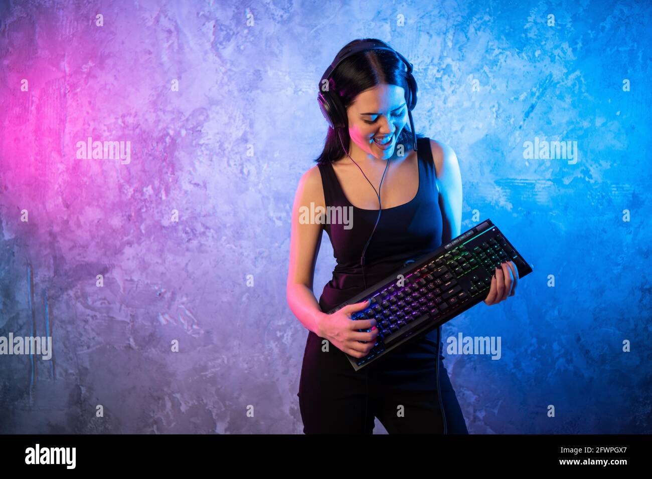 Female esports gamer posing with a gaming gear in neon light. Streamer ...