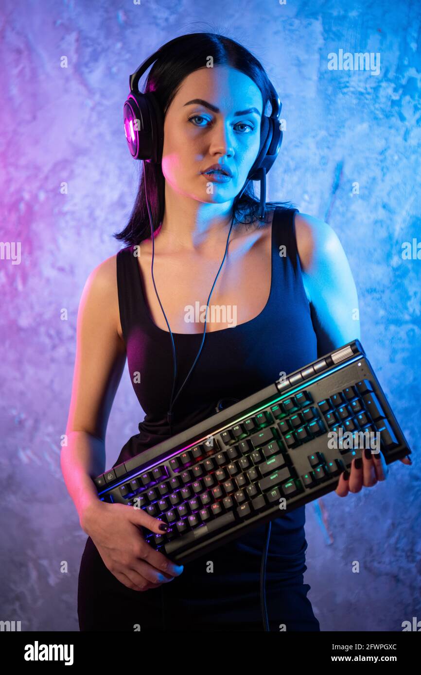 Female esports gamer posing with a gaming gear in neon light. Streamer ...