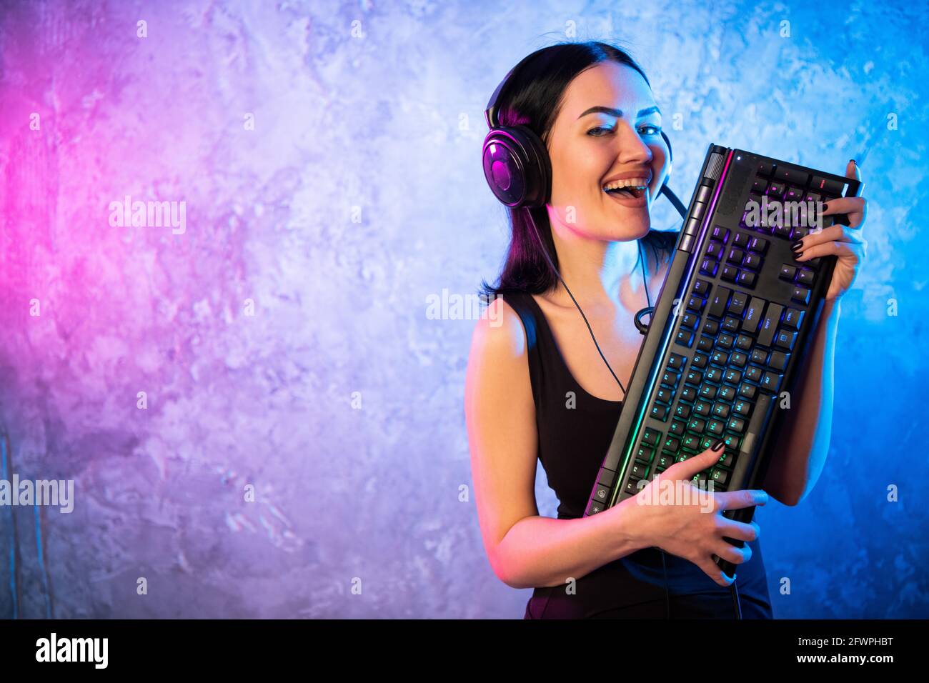Female esports gamer posing with a gaming gear in neon light. Streamer ...