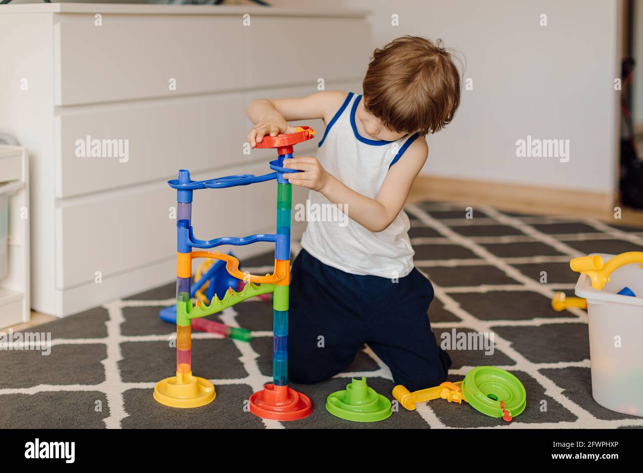 3 year old child is playing on floor at home. He designs and is totally ...