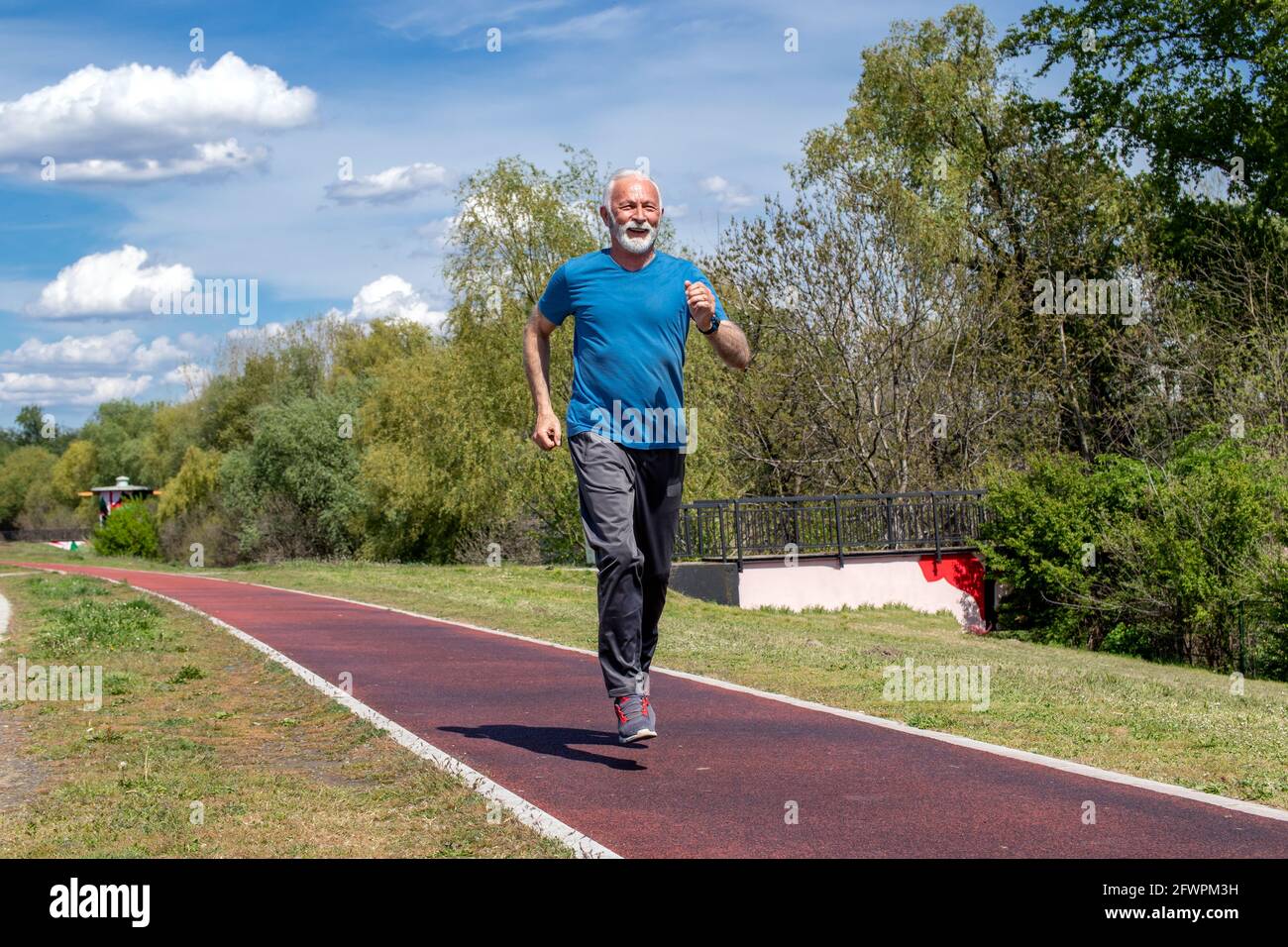 Senior man running on the jogging track on the quay Stock Photo - Alamy
