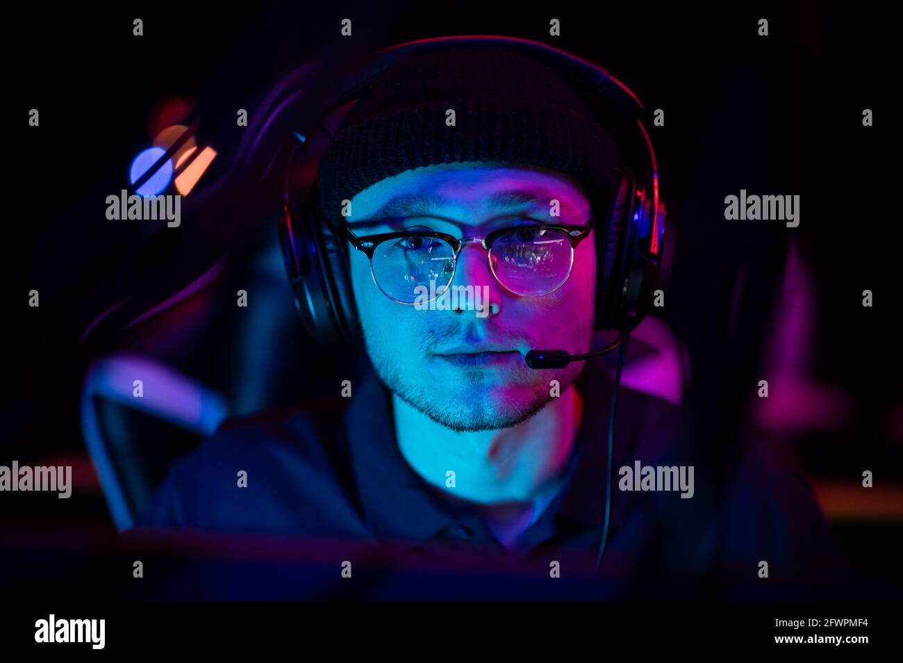 Close-up portrait of a young gamer at the computer. A gaming headset ...