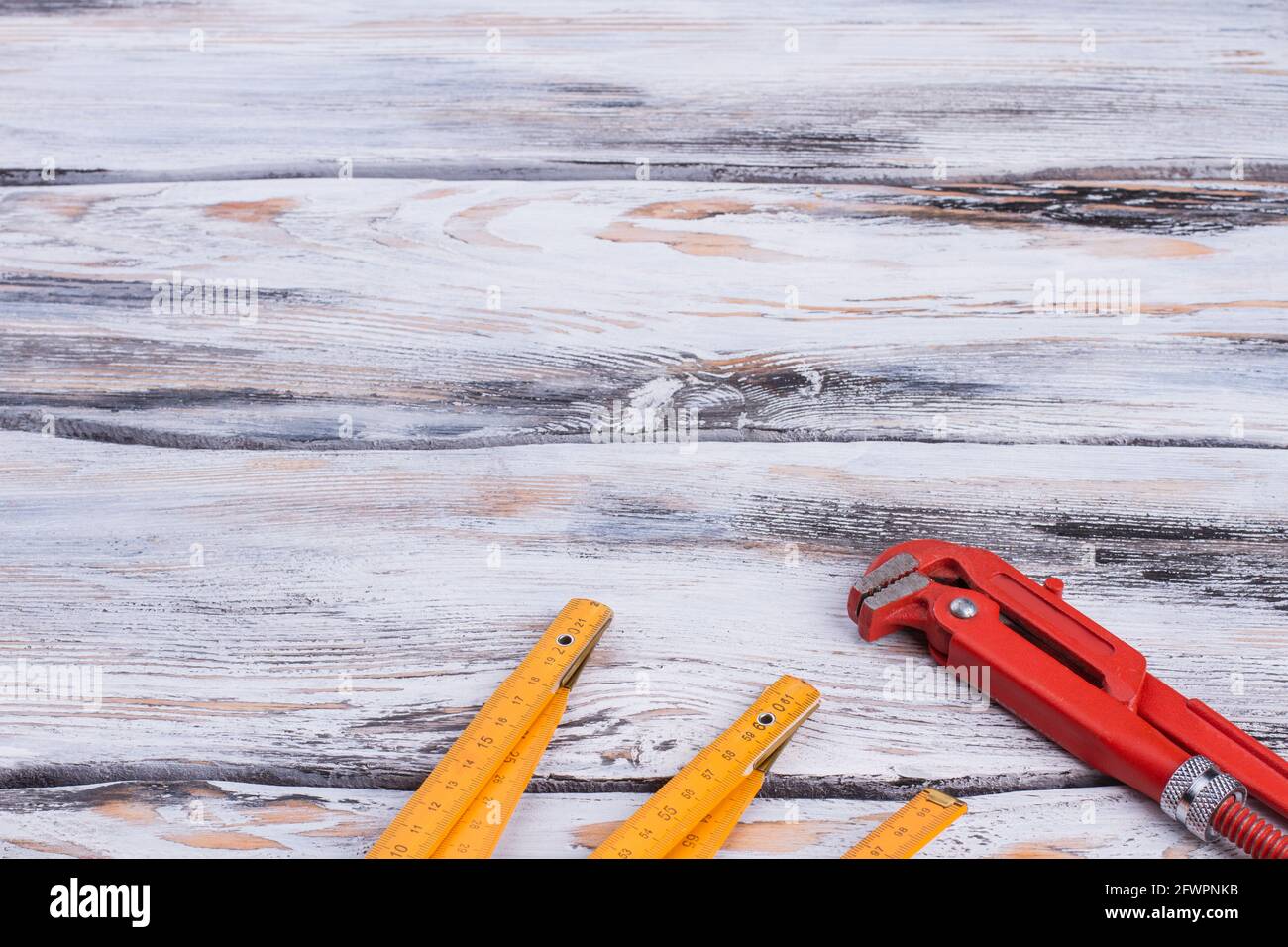 Adjustable wrench and folding ruler on wooden background Stock Photo ...