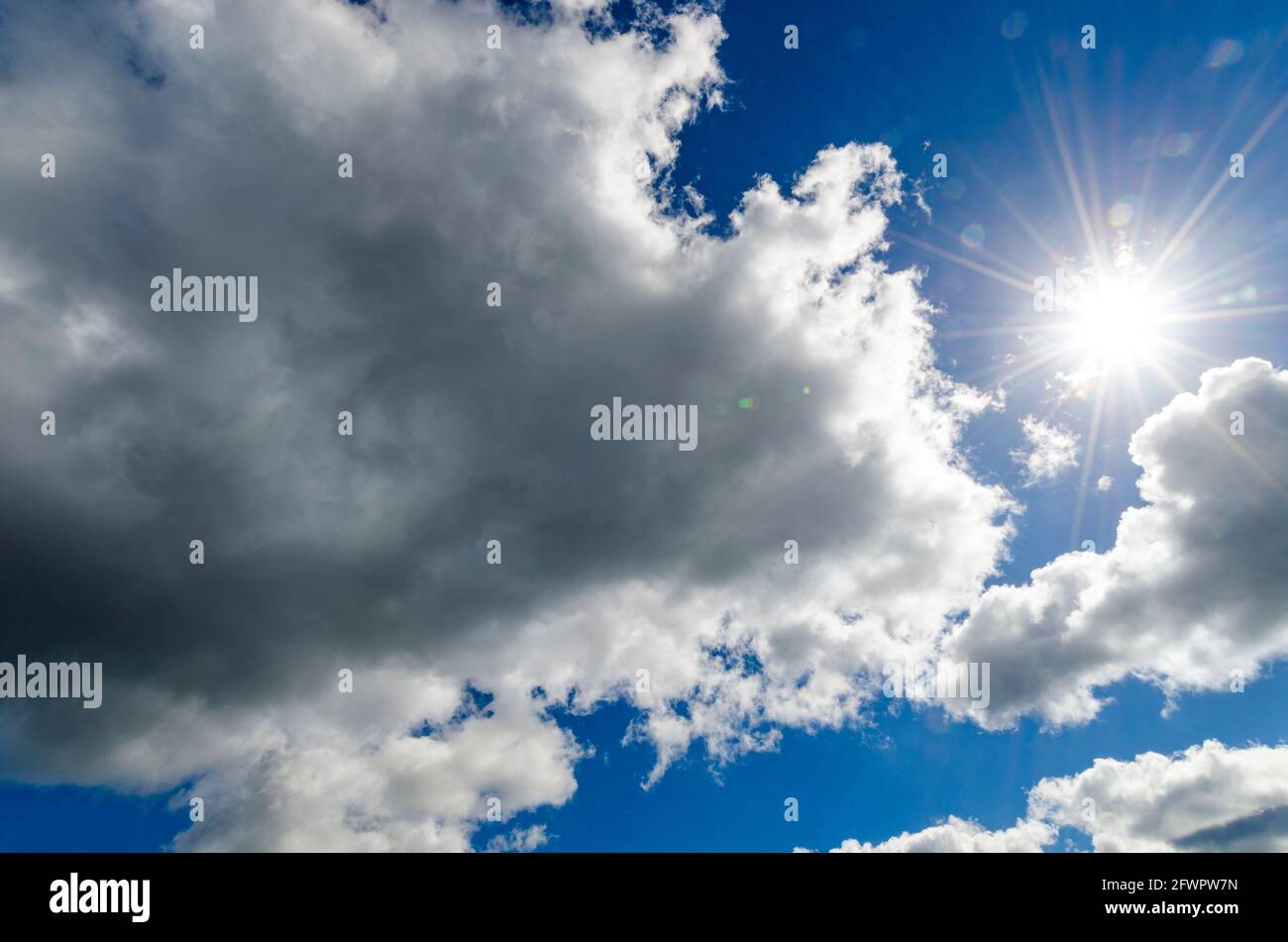 Bright sunburst with natural lens flare and sun rays in a blue summer ...