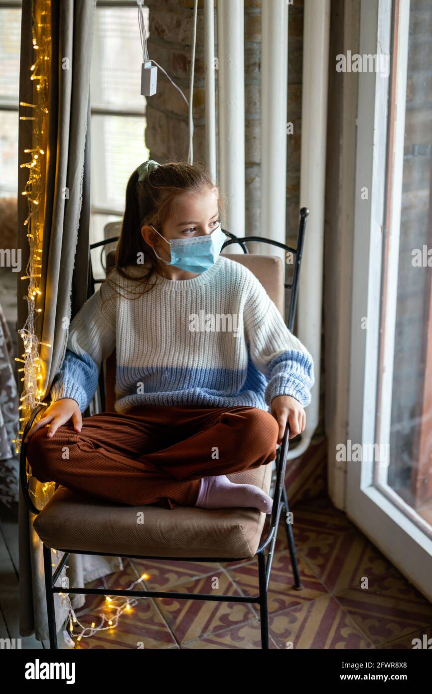 Sad child girl wearing protective mask at home. People coronavirus ...