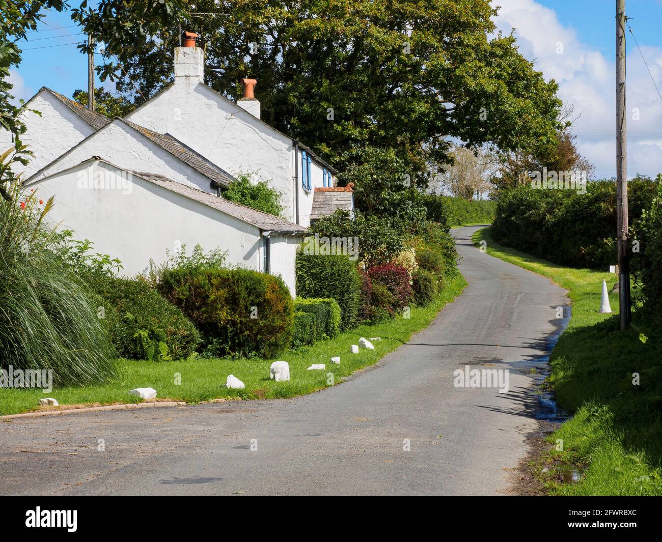 Small quiet road with pretty white house, the road crosses the boarder ...
