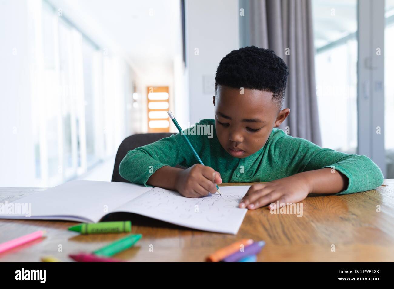 African american boy in online school class, writing in his notebook ...