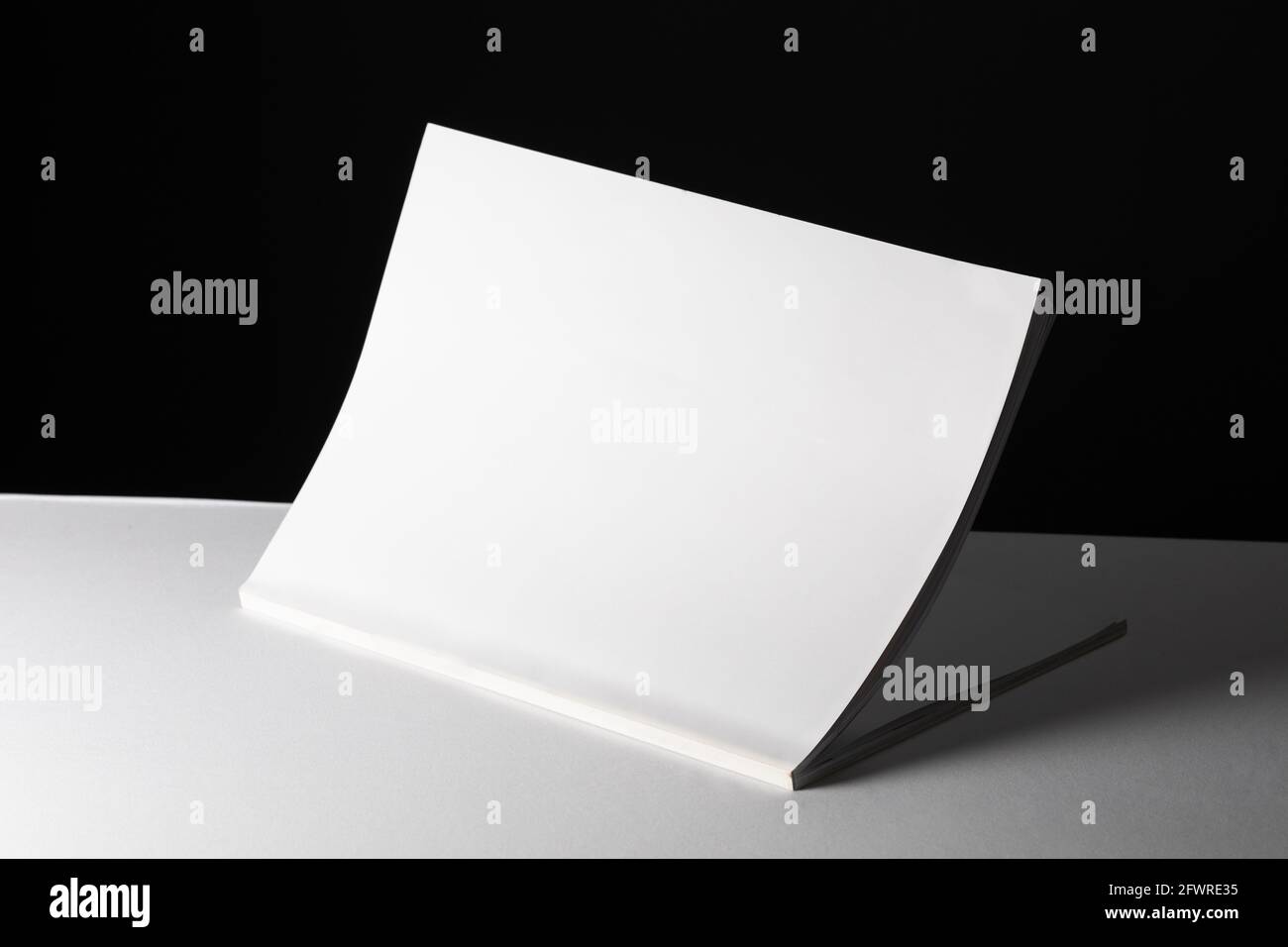 Composition of half opened book with blank pages on black and white ...