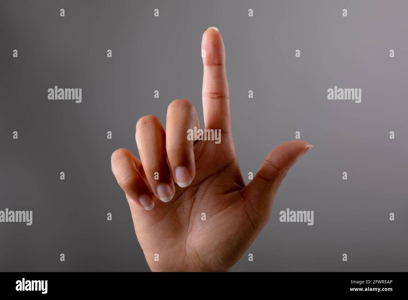Close up of hand touching invisible screen against grey background ...