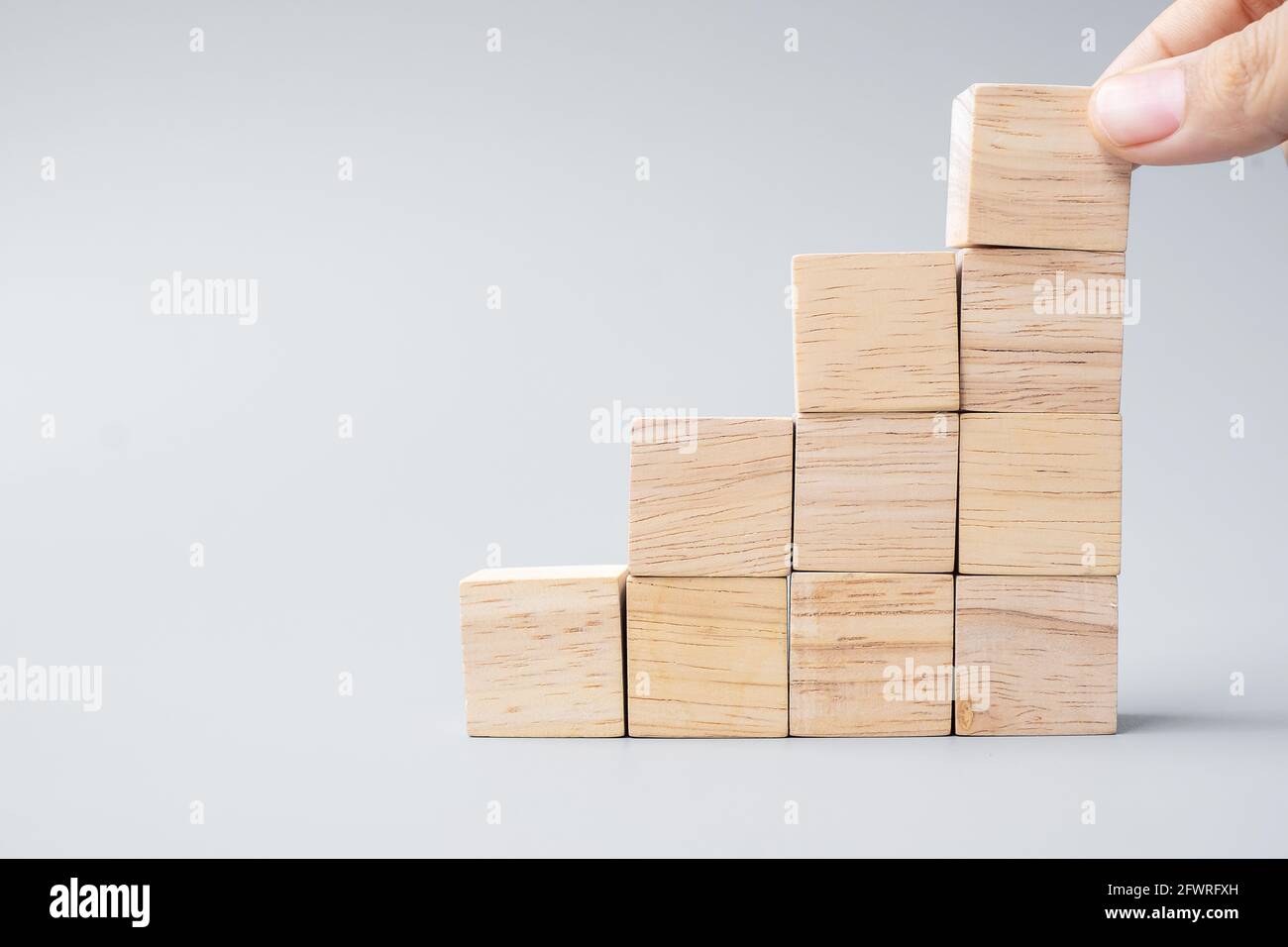 Businessman hand placing or pulling wooden block on the building ...
