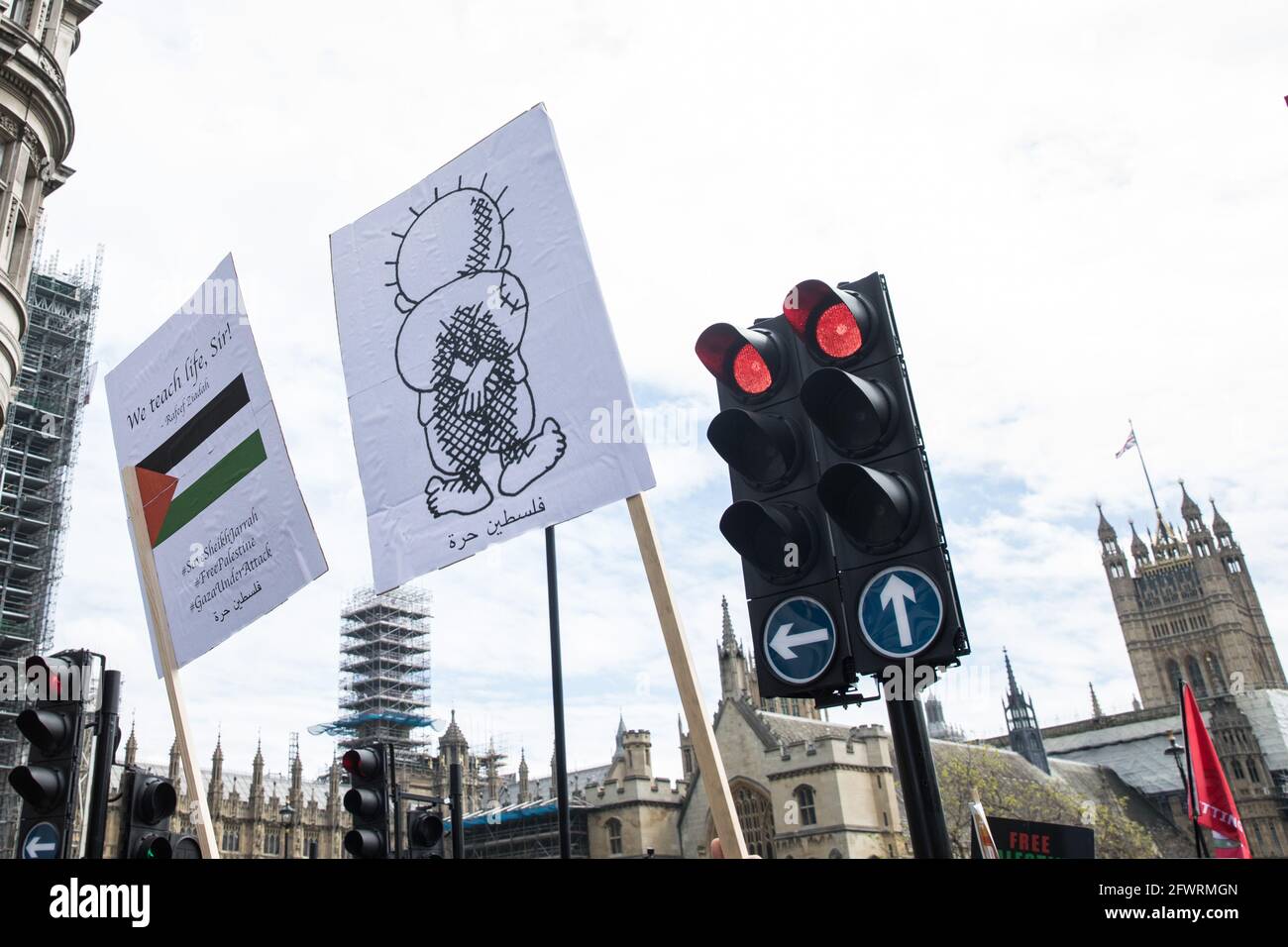 London, UK. 22nd May, 2021. A man passes Parliament holding a placard ...