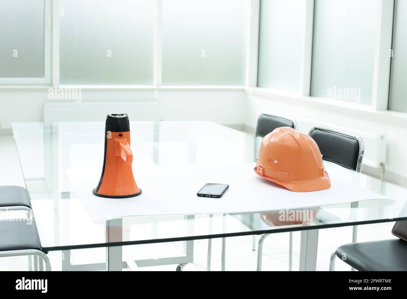 Loudspeaker construction hard hat on glass table in office space Stock ...