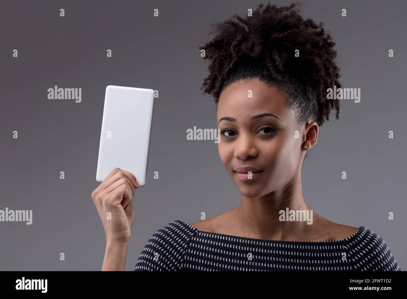 Serious young Black woman holding up a modern mobile phone on display ...