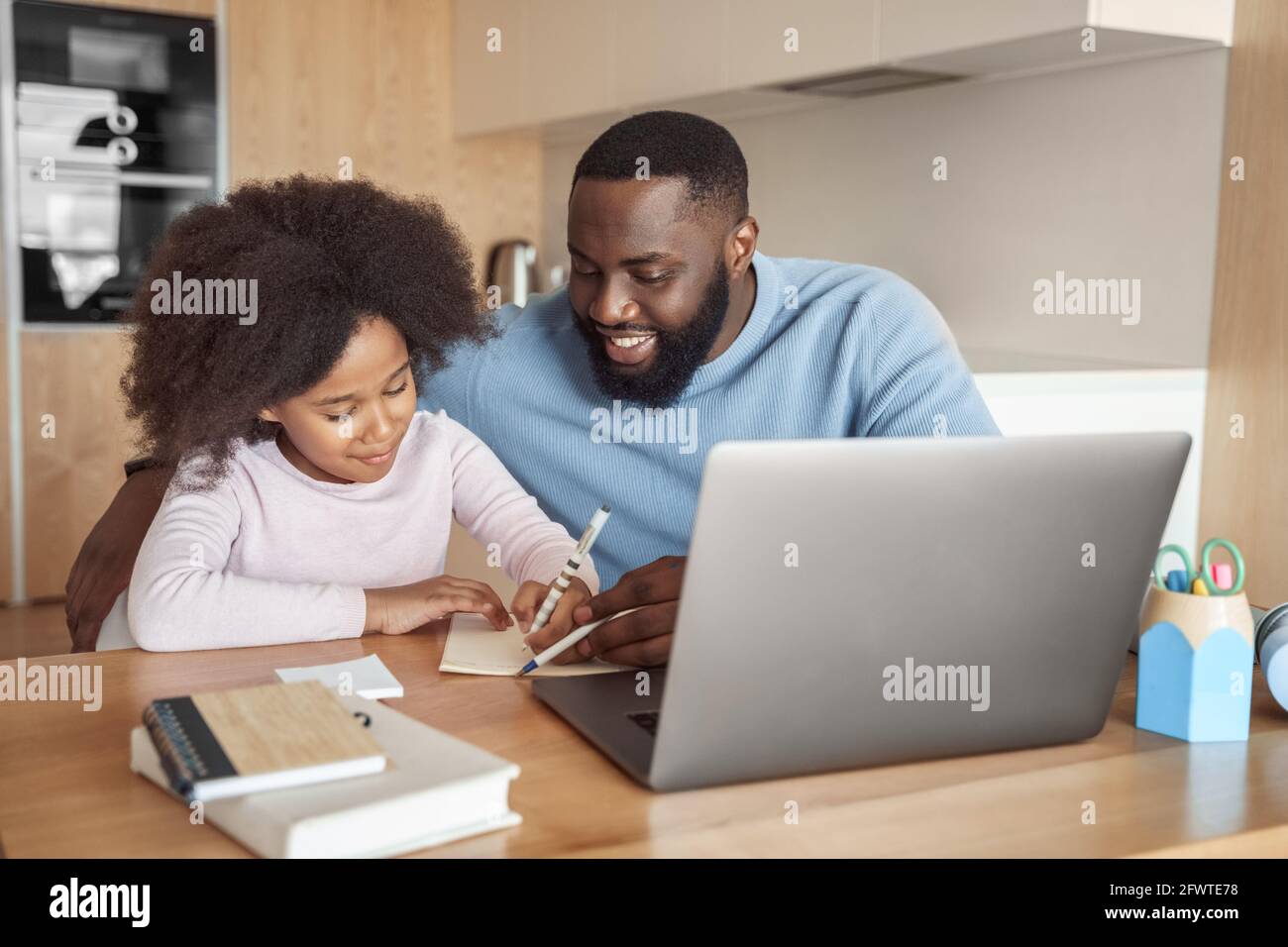 Caring happy father help cheerful little daughter with school subject ...