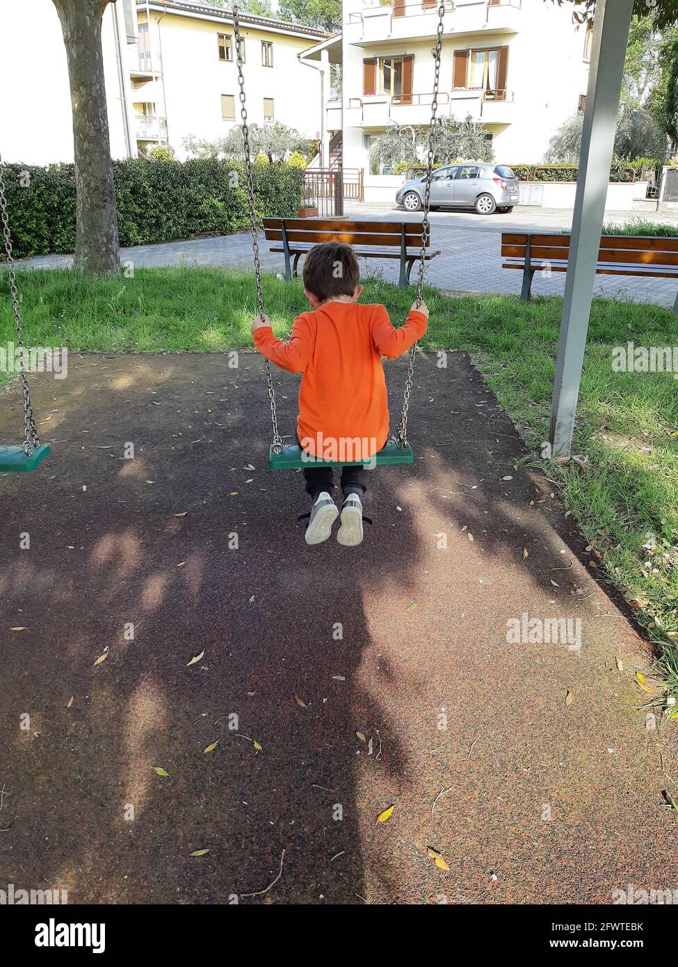 Rear view of a child playing on the swing Stock Photo - Alamy