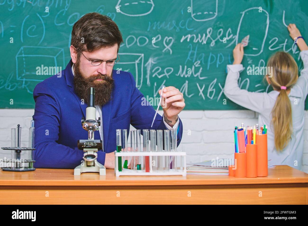 Performing an experiment. Teacher and pupil. Male teacher giving lesson ...