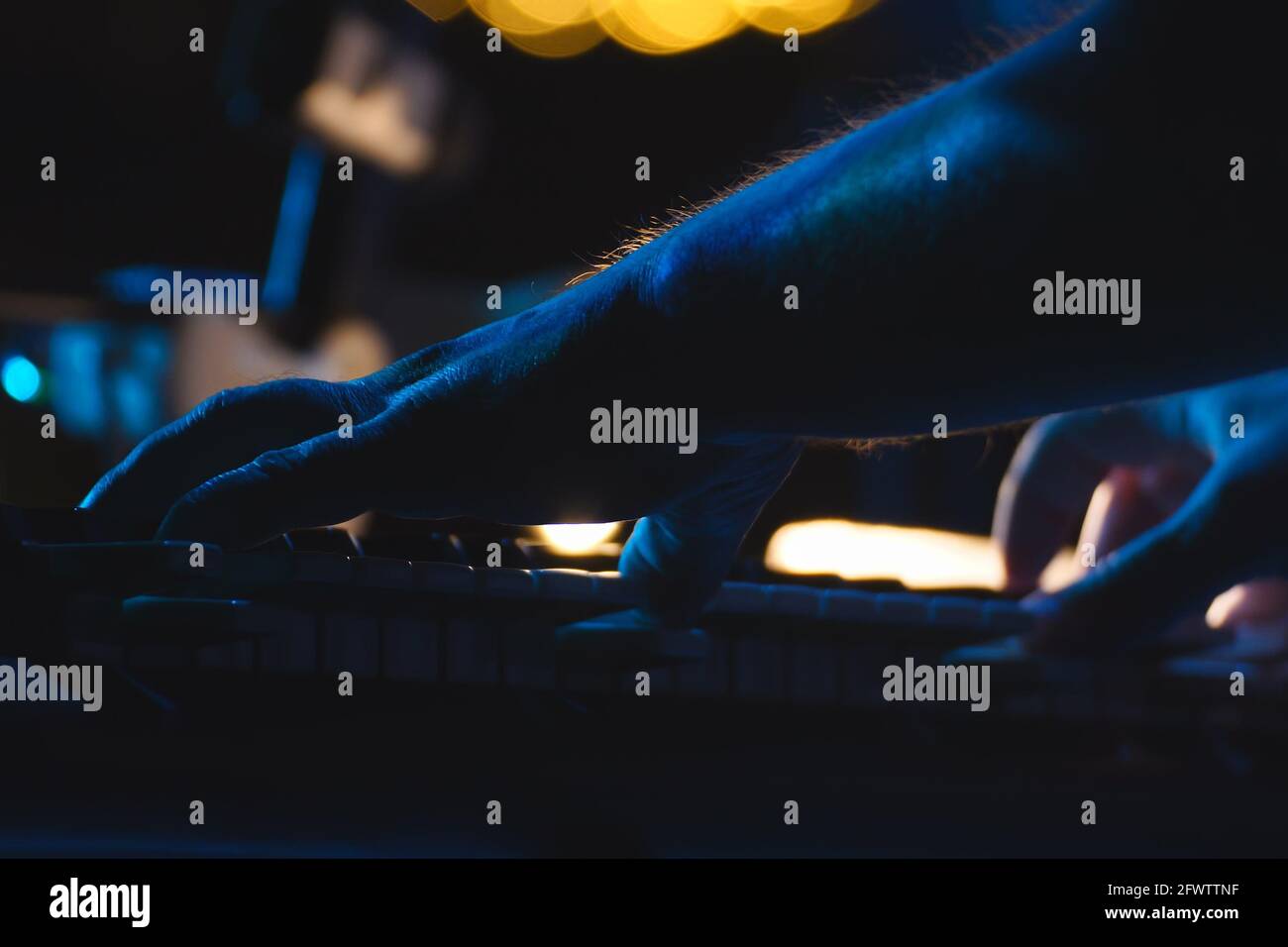 A keyboardist plays a synthesizer in the spotlight. The singer is seen ...