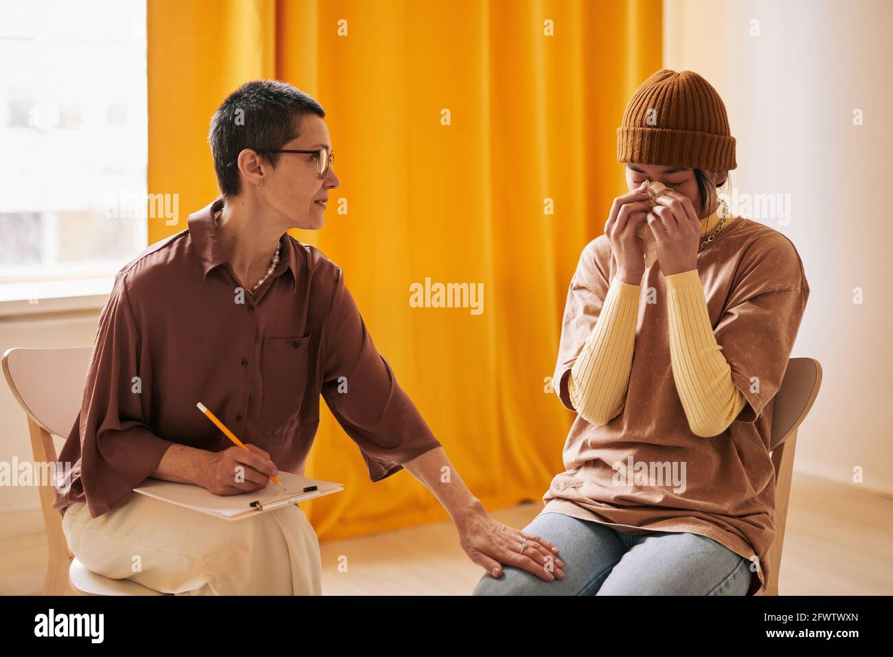 Portrait Of Short Haired Female Psychologist Comforting Young Woman
