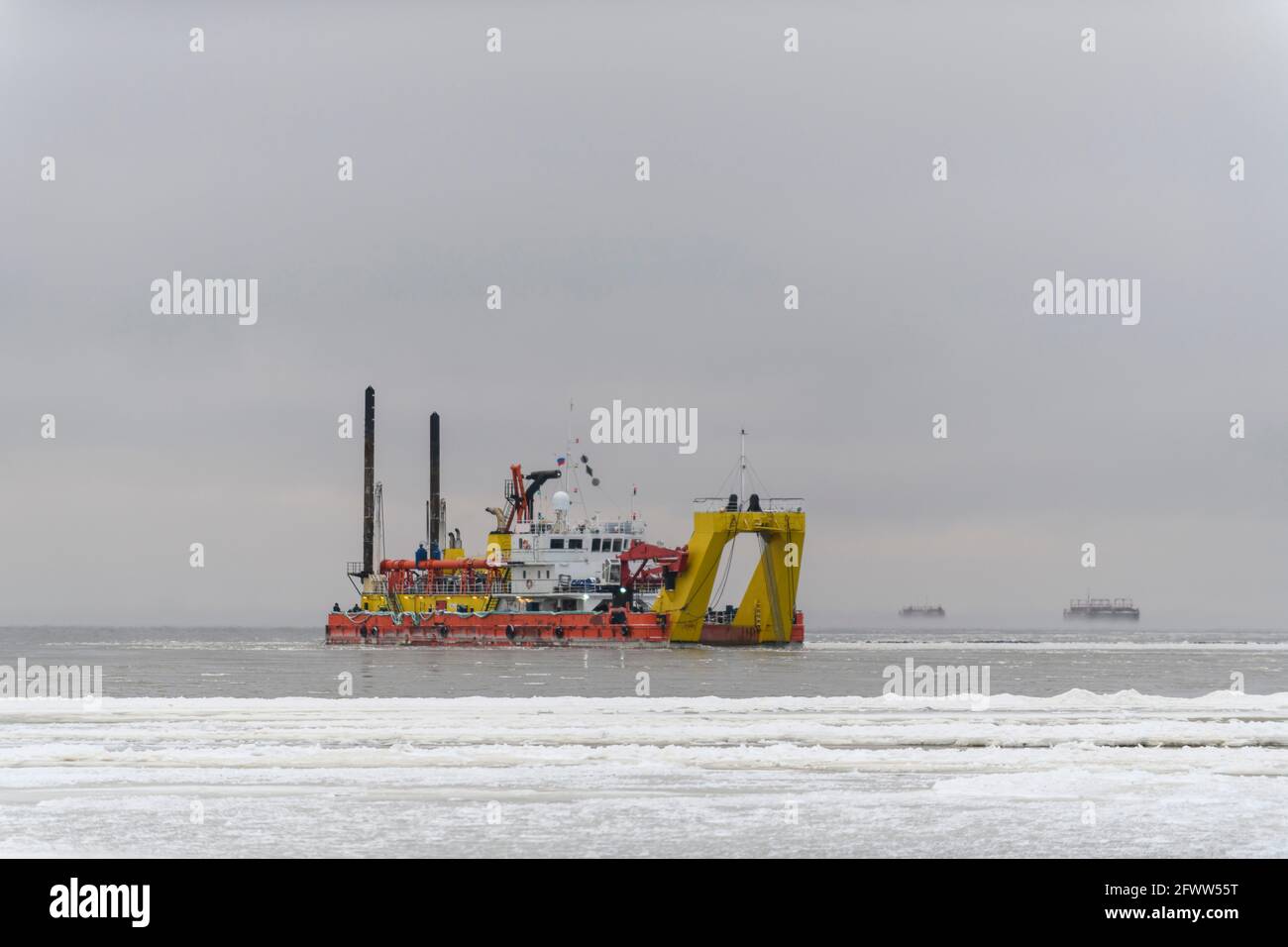 Vessel engaged in dredging at sunset time. Hopper dredger working at ...